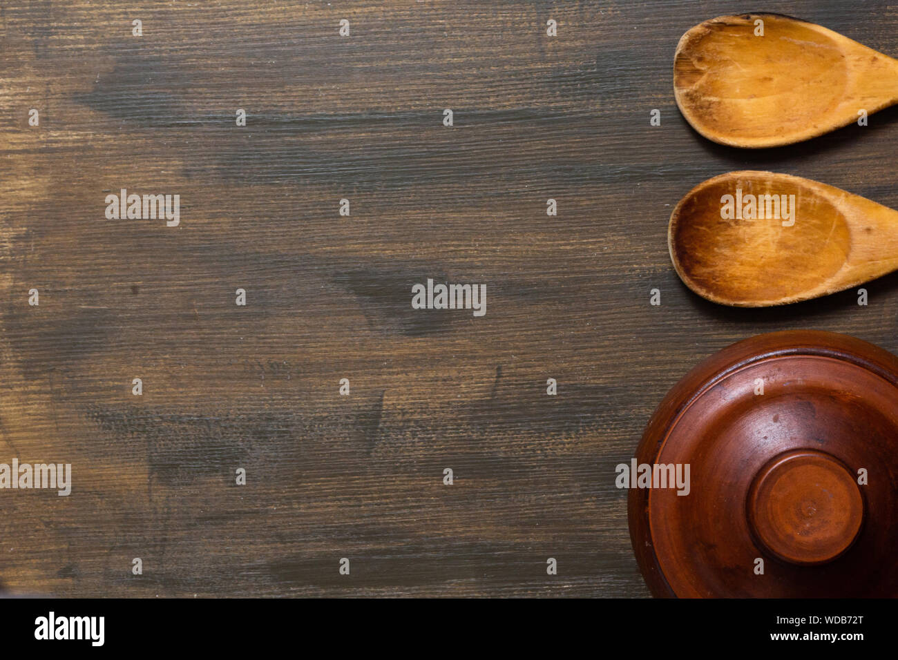 Top view of clay pot and wooden spoons on the wooden background with ...