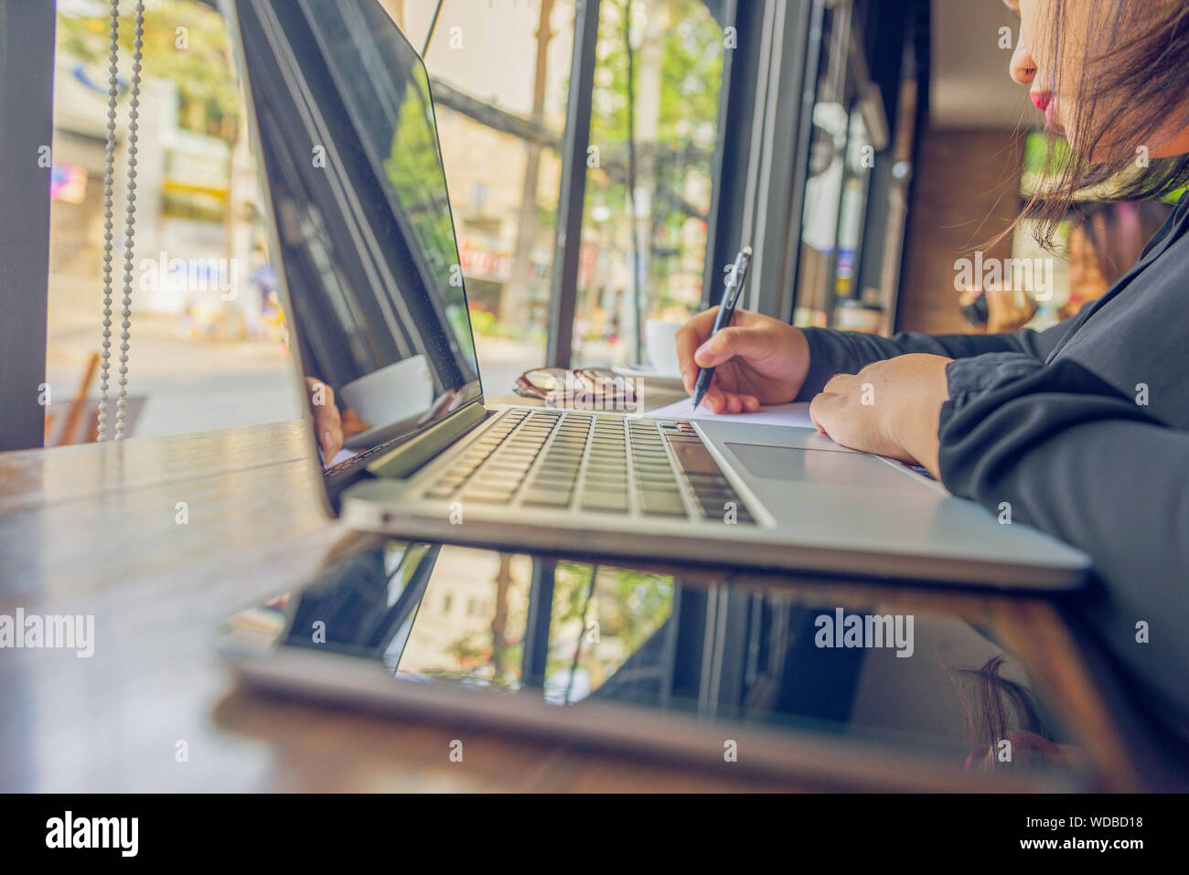 Woman hand writing next to laptop cellphone on desk Stock Photo - Alamy