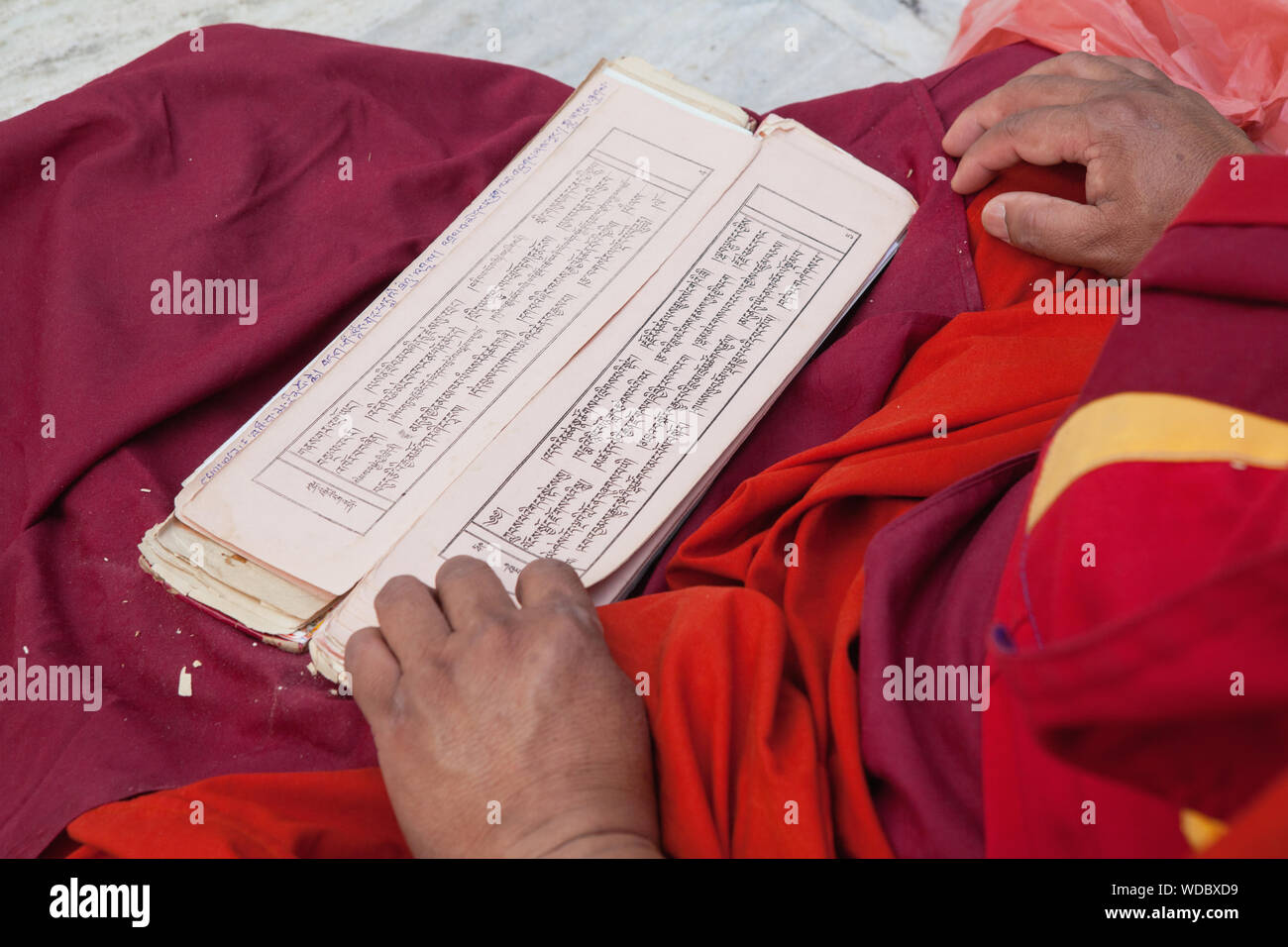 India, Bihar, Bodhgaya, Prayer cards in the lap of a monk at the ...