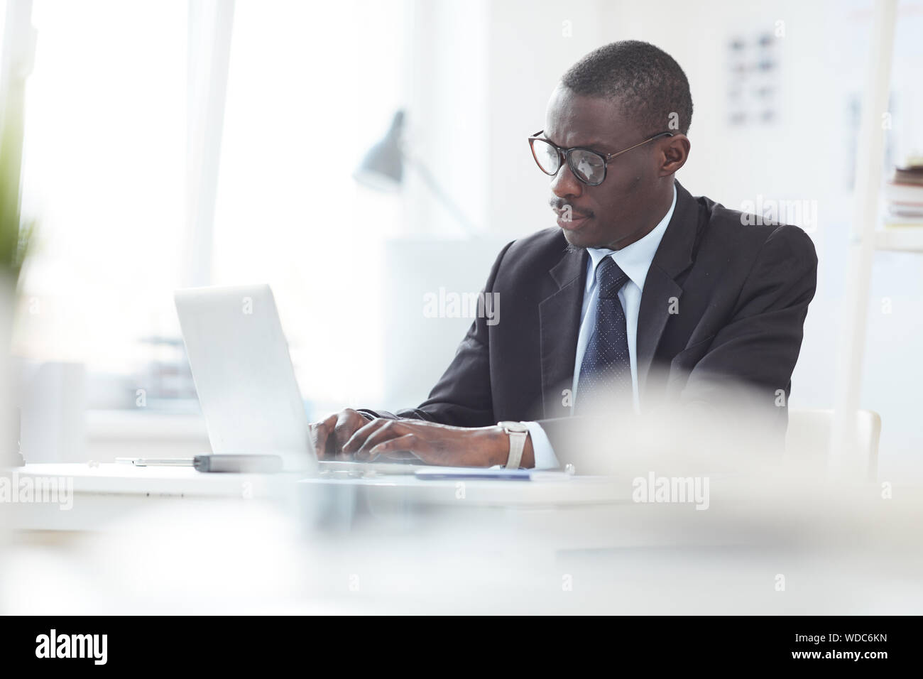 African male leader concentrating at his work at office he sitting at ...