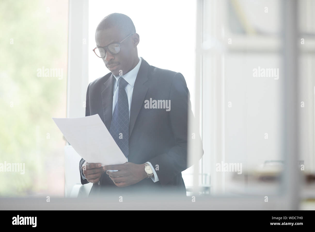 Serious African manager in formal wear standing and examining the ...