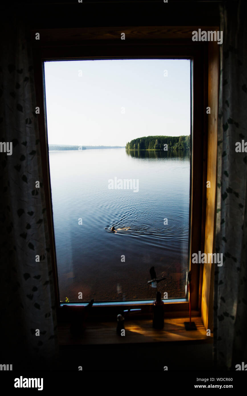 View of woman swimming in lake through window Stock Photo - Alamy