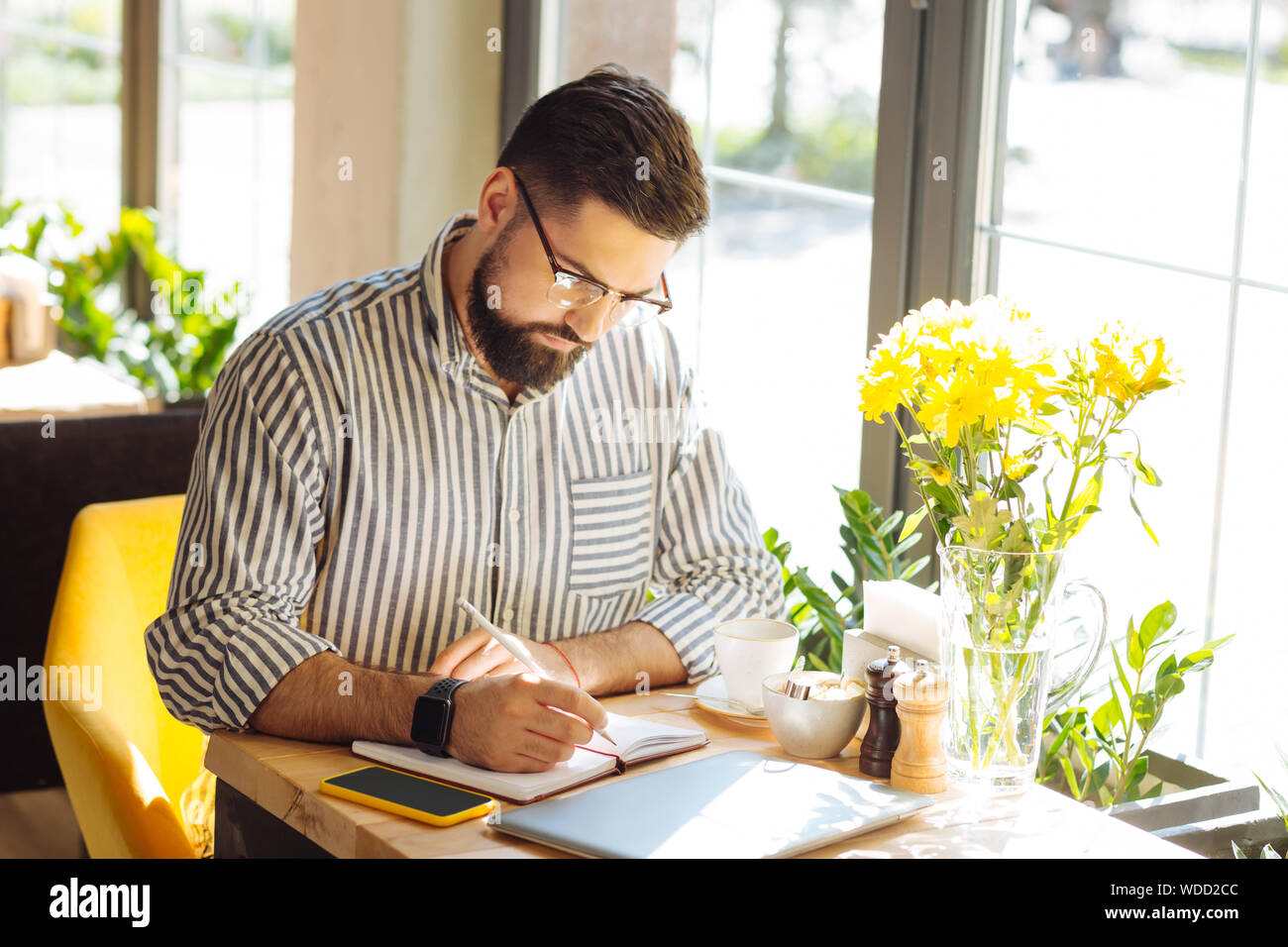 Serious bearded man writing in his notebook Stock Photo - Alamy
