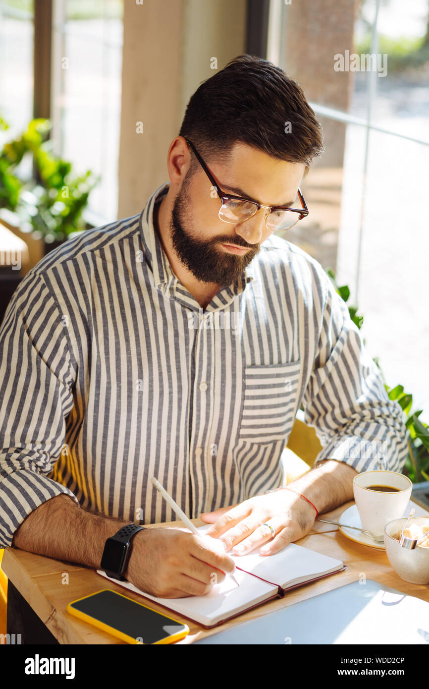 Good looking serious man writing in the notebook Stock Photo - Alamy