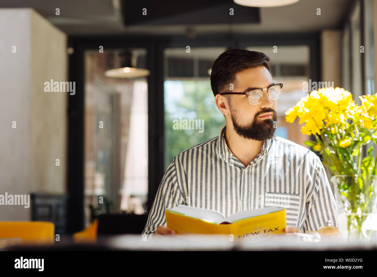 Serious nice man thinking about the book Stock Photo - Alamy
