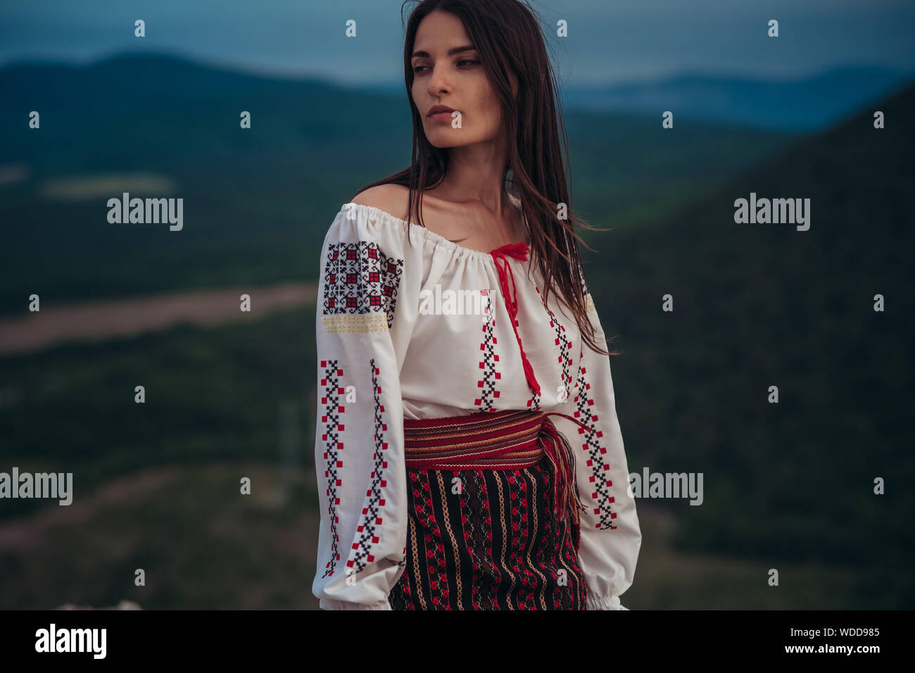 Atractive woman in traditional romanian costume on mountain green ...
