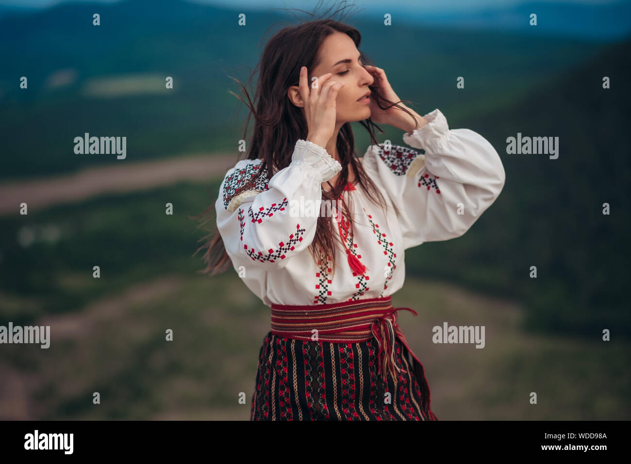 Atractive woman in traditional romanian costume on mountain green ...