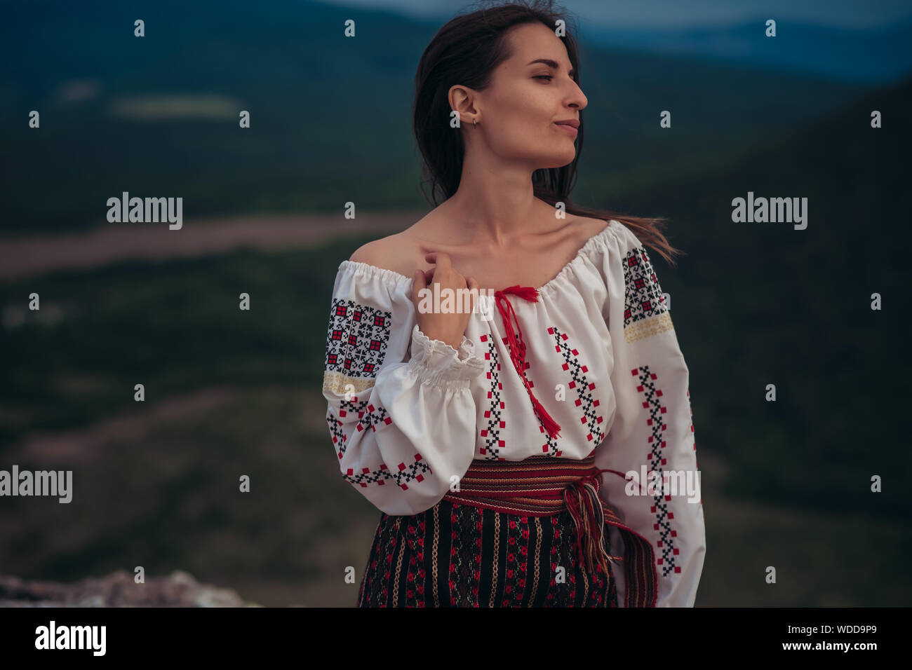 Atractive woman in traditional romanian costume on mountain green ...