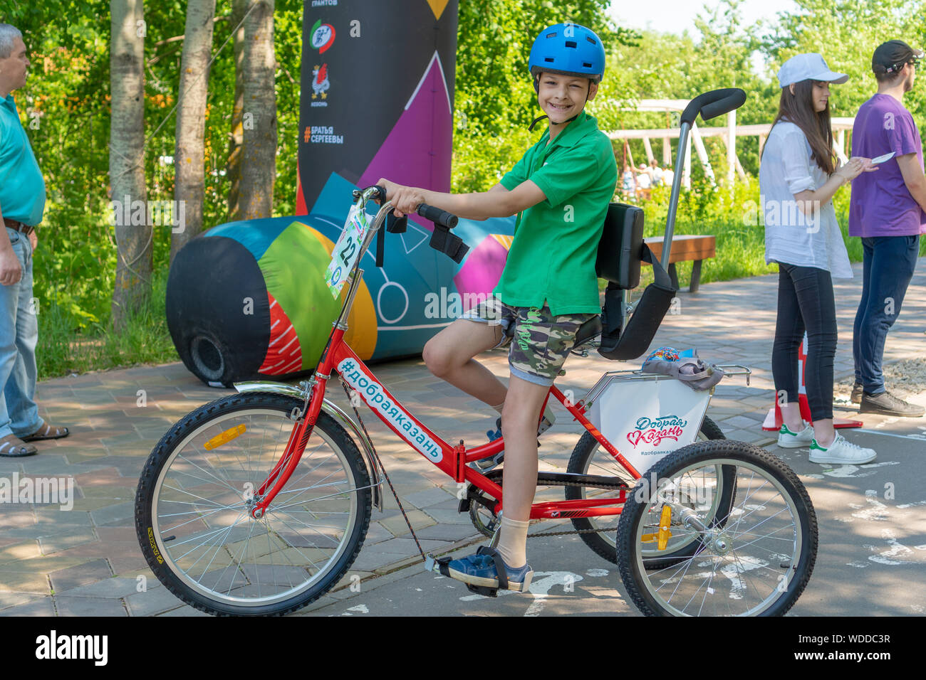 Russia, Kazan - May 31, 2019: Disabled boy in glasses on a tricycle on ...
