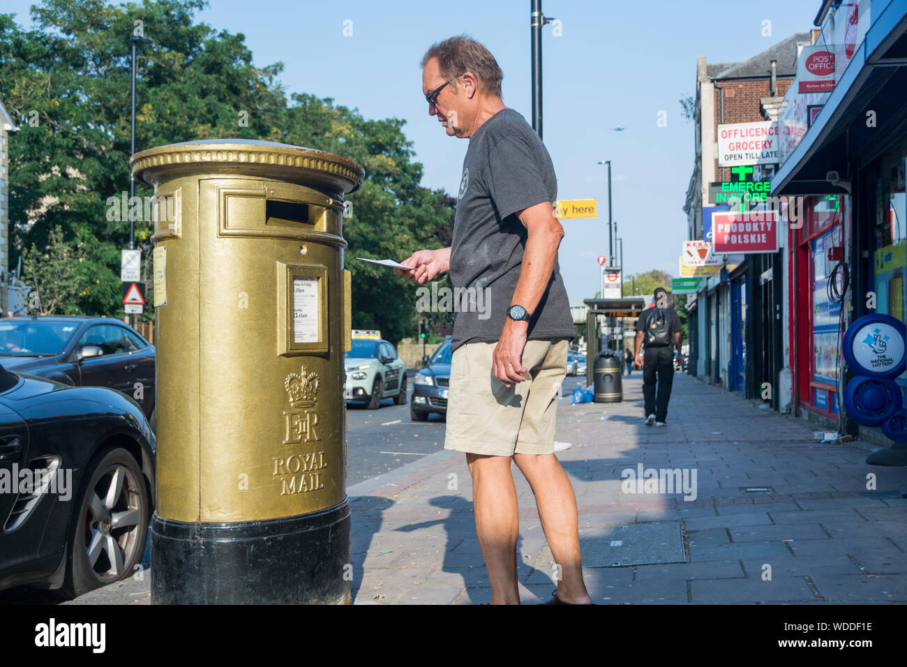 A man posting a letter in a gold post box in Isleworth to commemorate ...