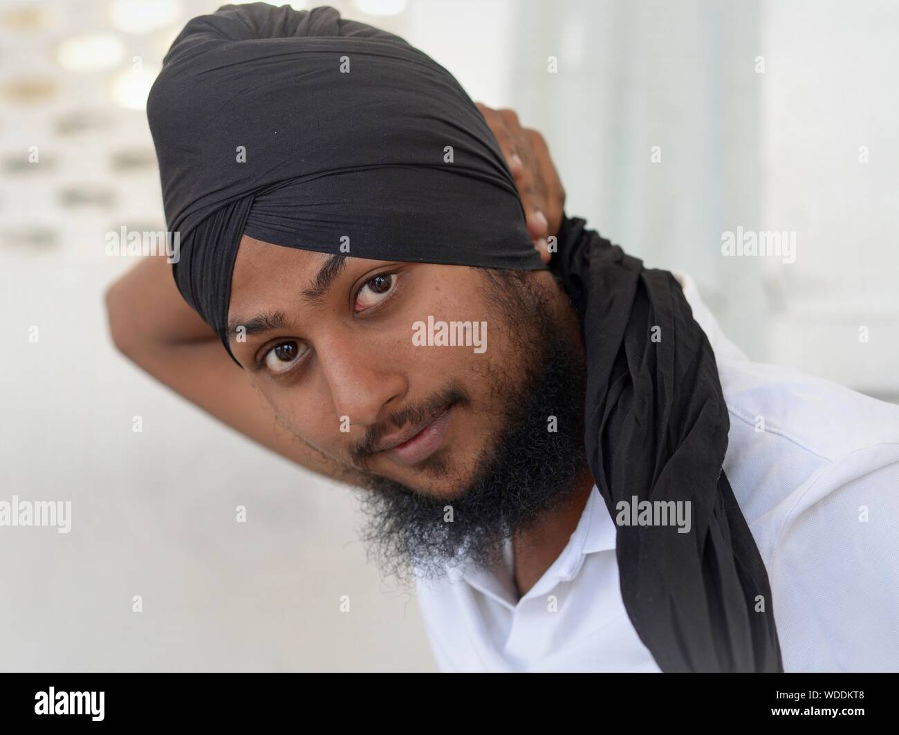 Young Indian Sikh devotee ties his traditional Sikh turban (dastar) and ...