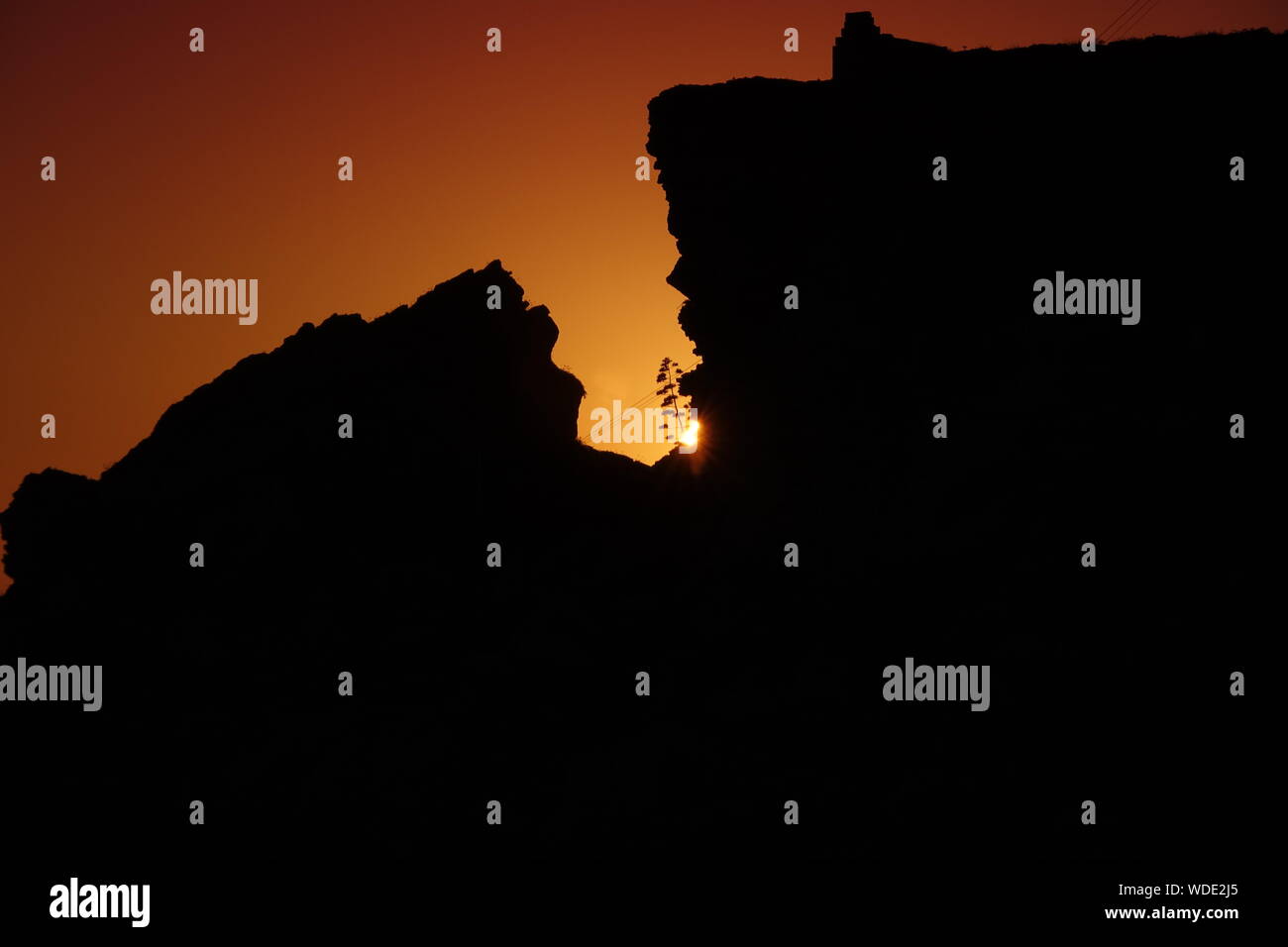 sunset through gap in cliff Stock Photo - Alamy