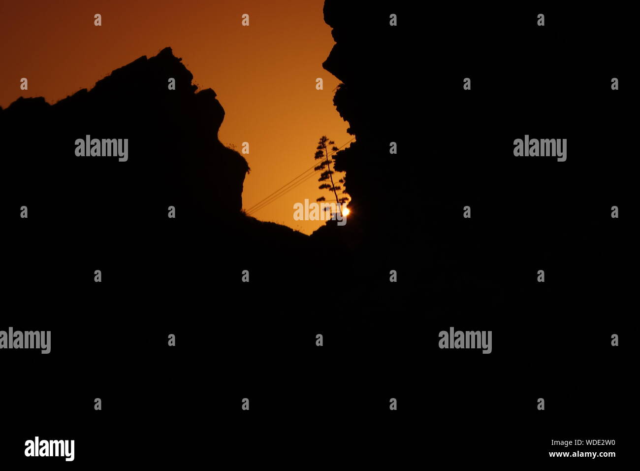 sunset through gap in cliff Stock Photo - Alamy