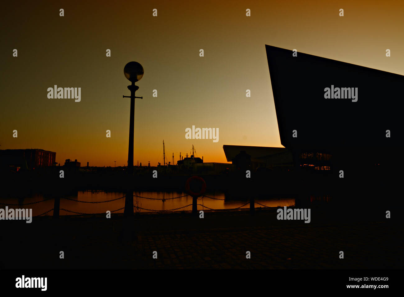 Liverpool waterfront buildings and ships masts in silhouette against a ...