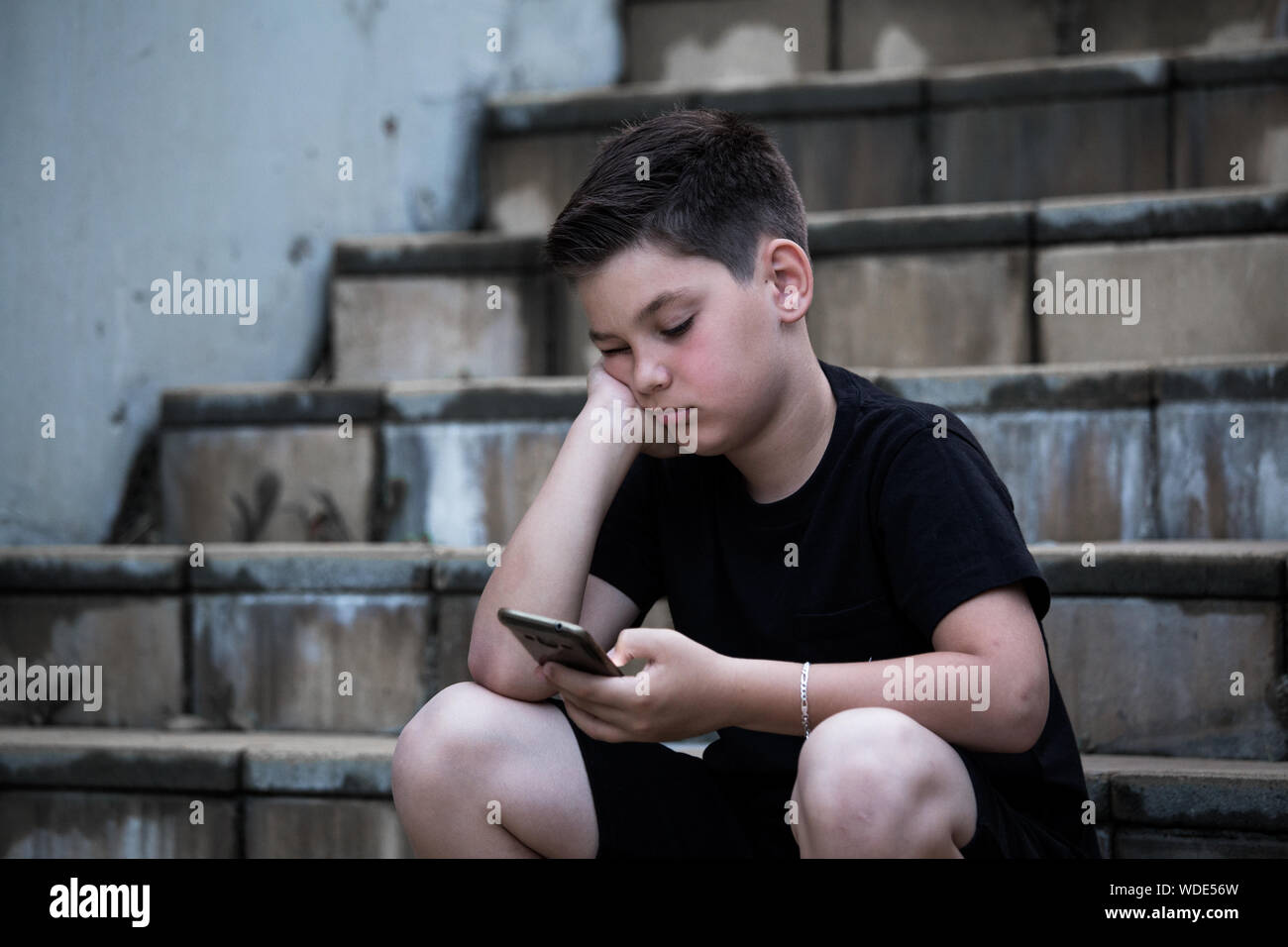 Sad Boy Looking At Mobile Phone With Hand On Head Stock Photo - Alamy