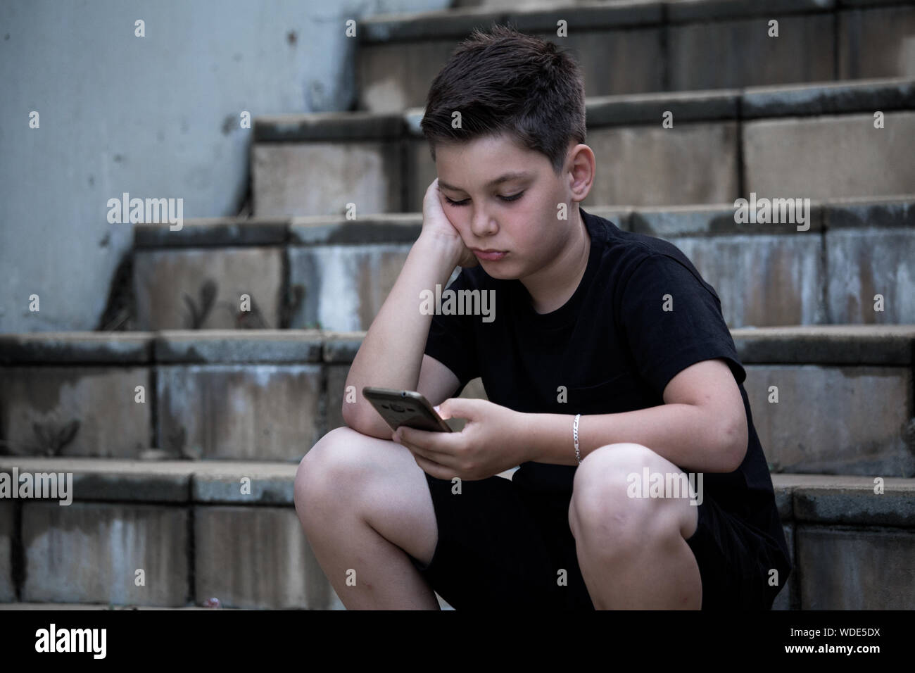 Sad Boy Looking At Mobile Phone With Hand On Head Stock Photo - Alamy