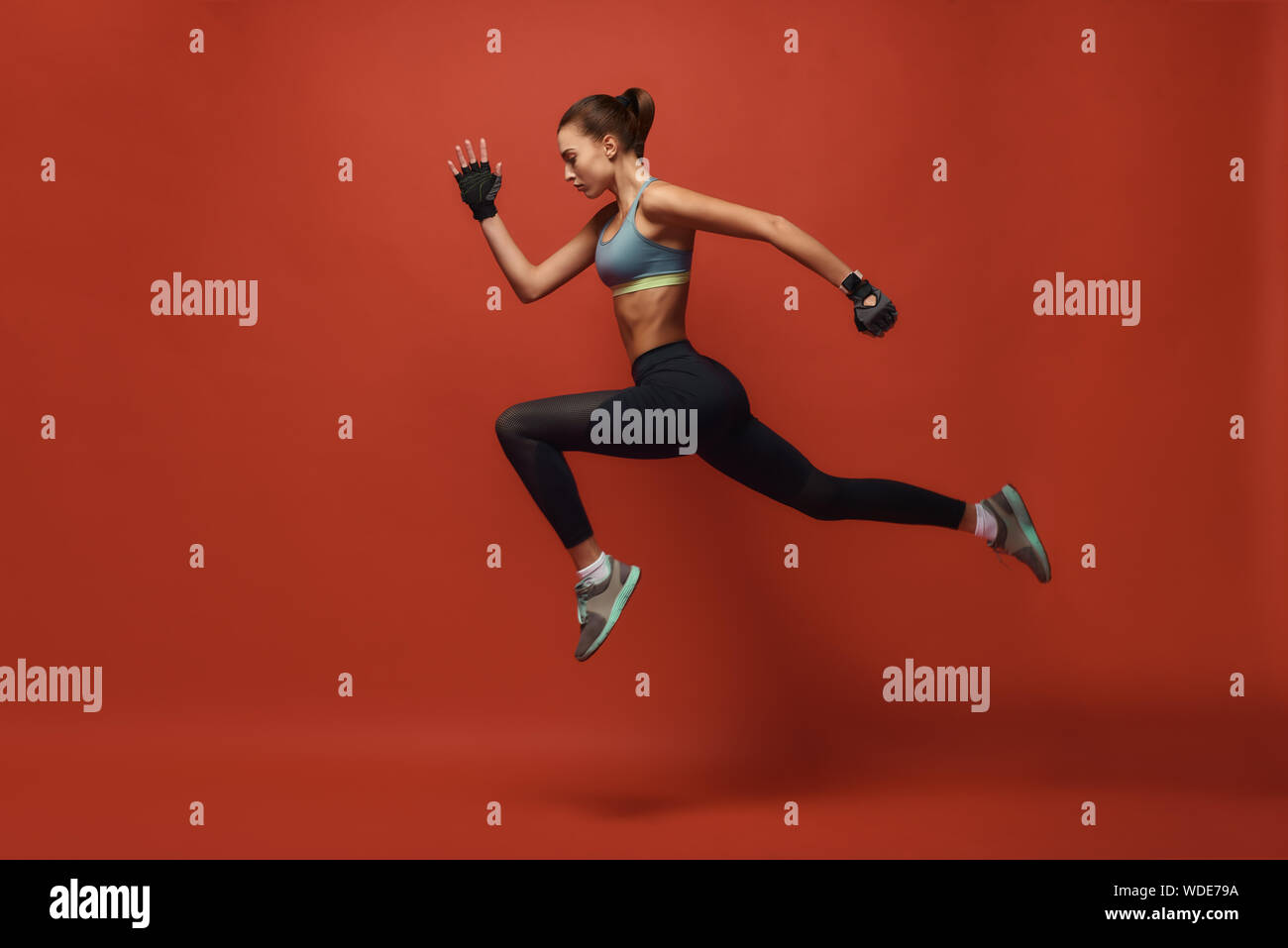 Full-length portrait of young girl in sportswear jumping isolated over ...