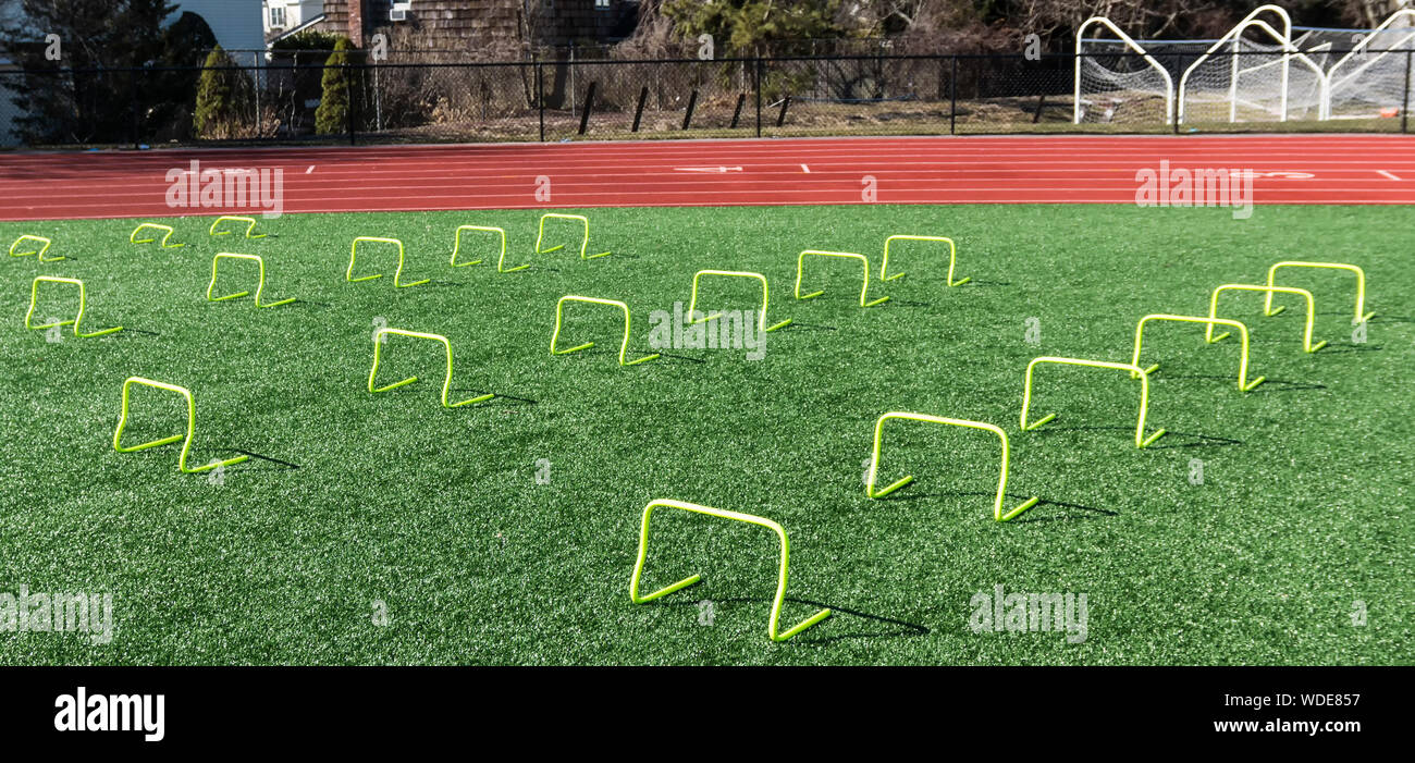 Front view of yellow mini banana hurdles set up for speed work during track and field practice ...