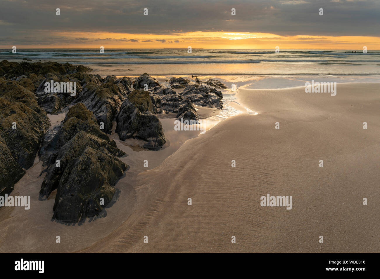 Waves surround the rocks at Combesgate beach in north devon at sunset ...