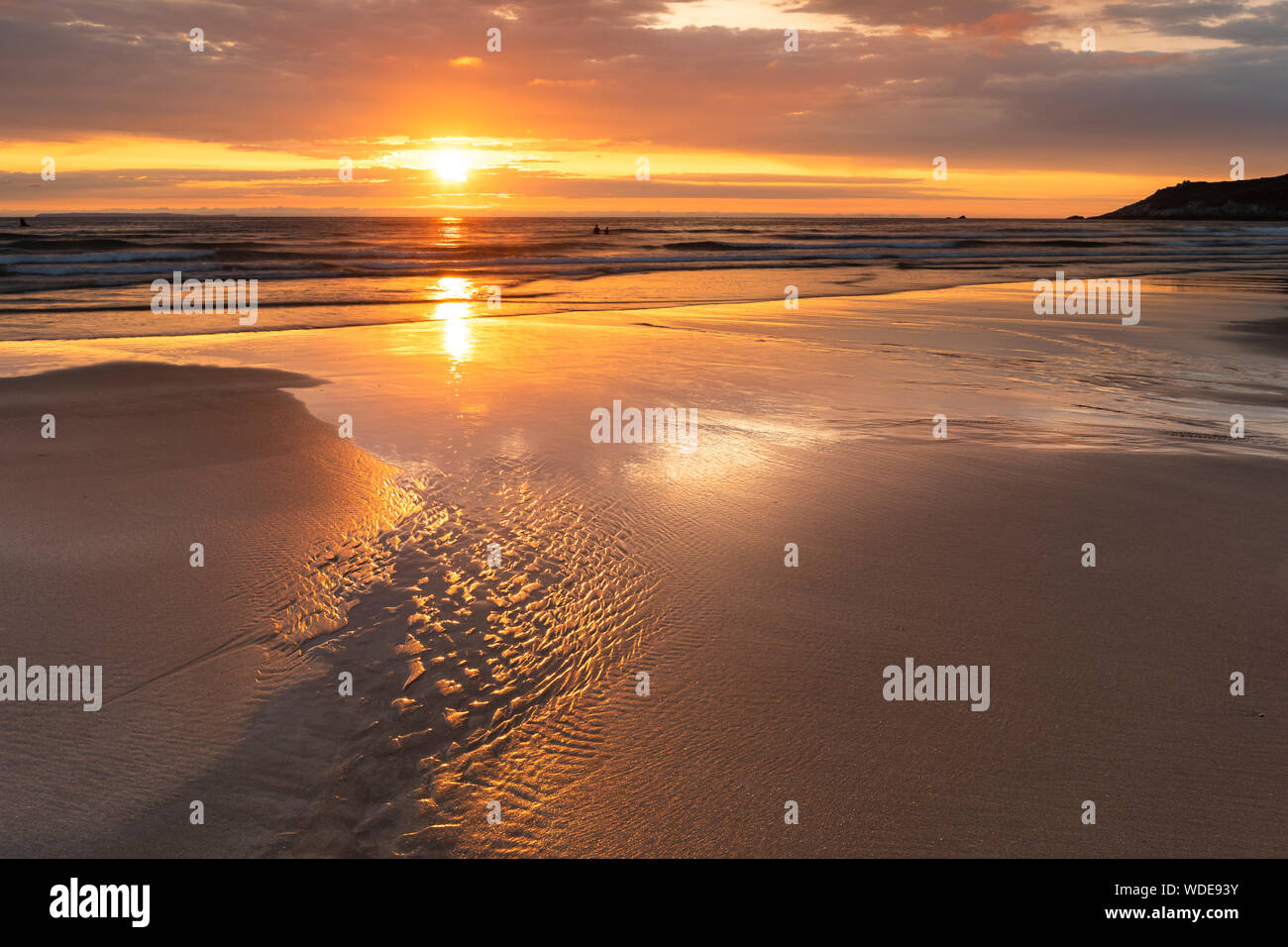 Surfers enjoy the waves at combesgate beach on north devon at sunset ...