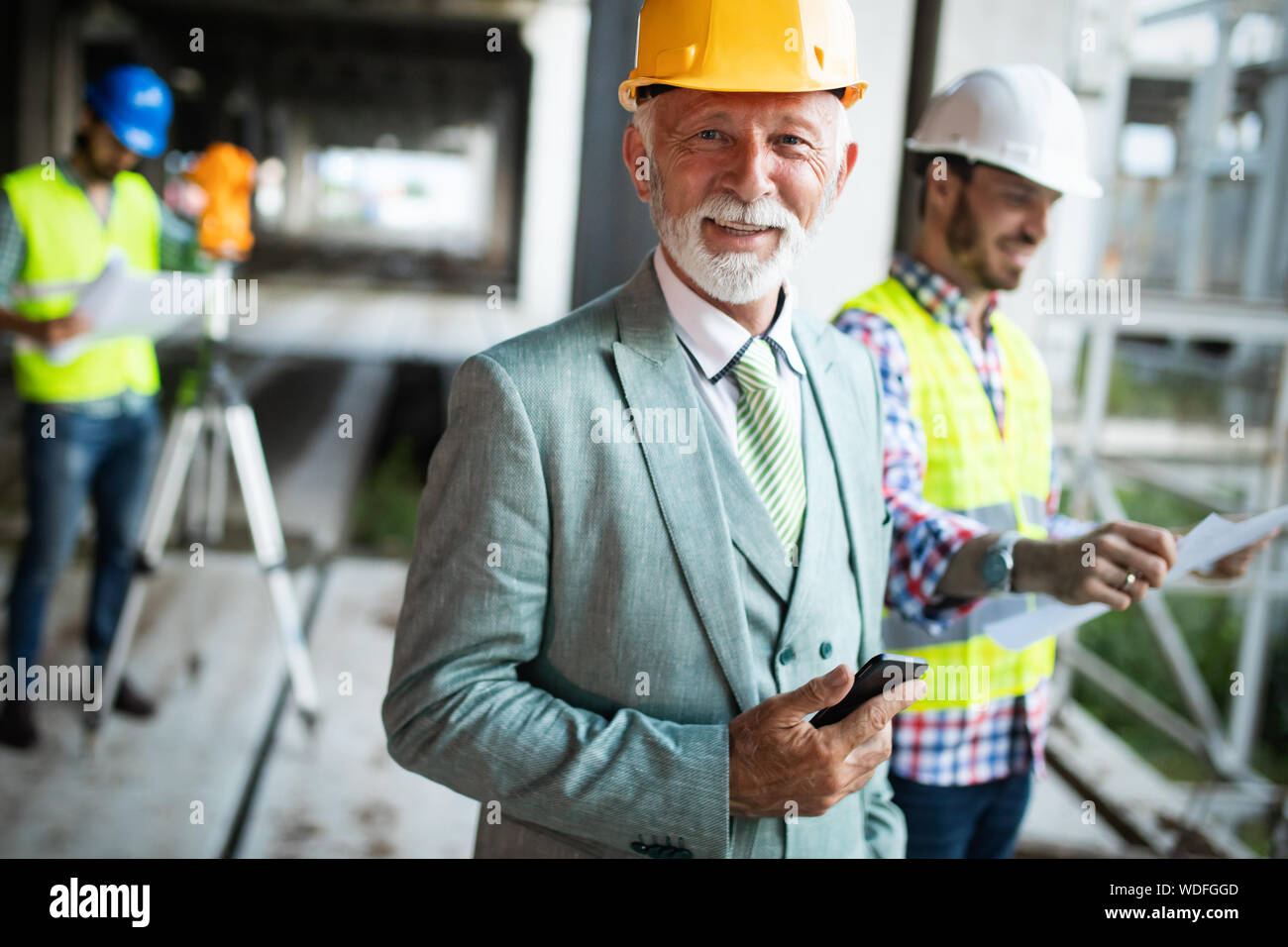 Engineer, foreman and worker discussing in building construction site ...