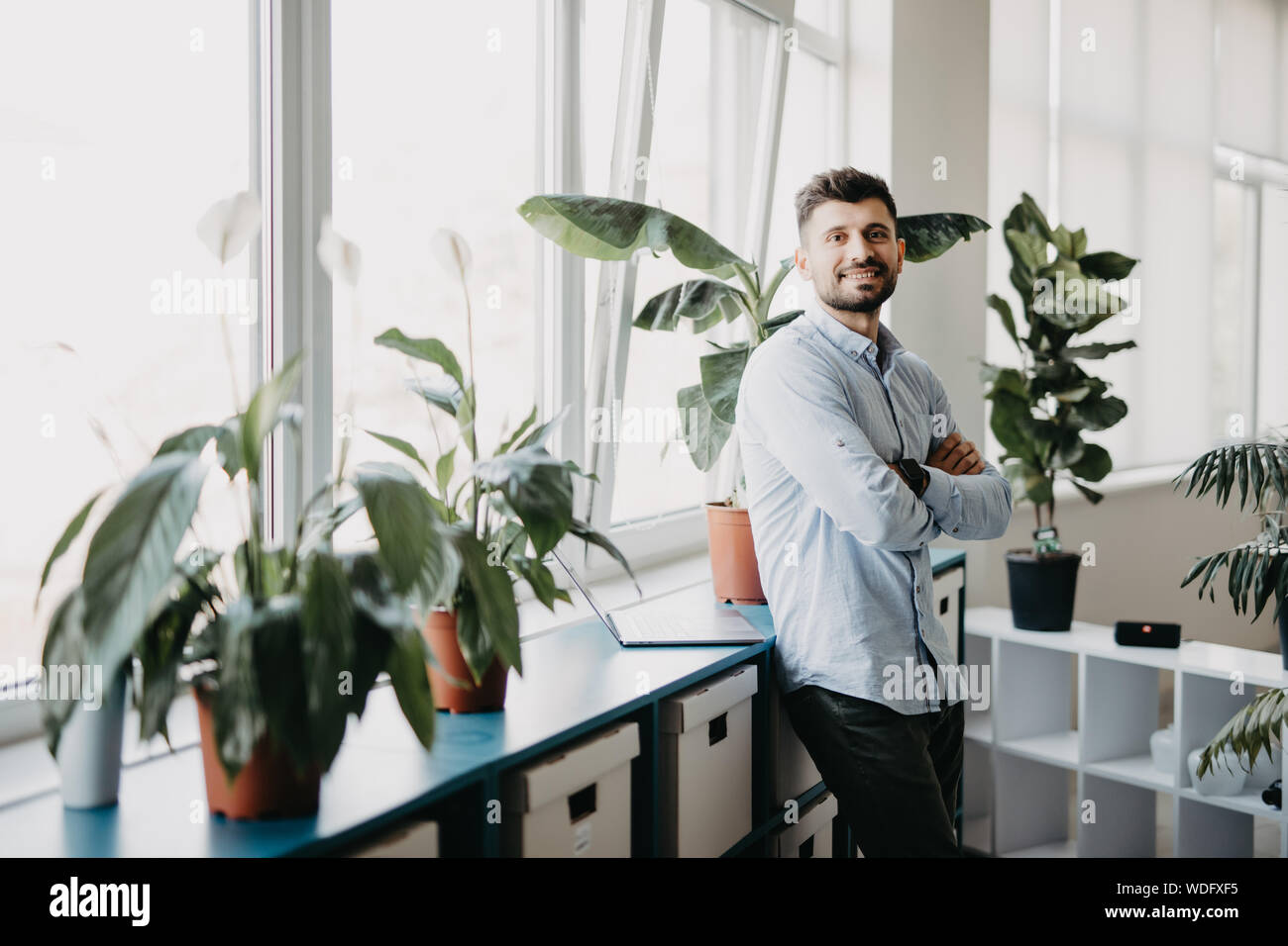 Smiling clerk standing in office with hands crossed on his chest ...