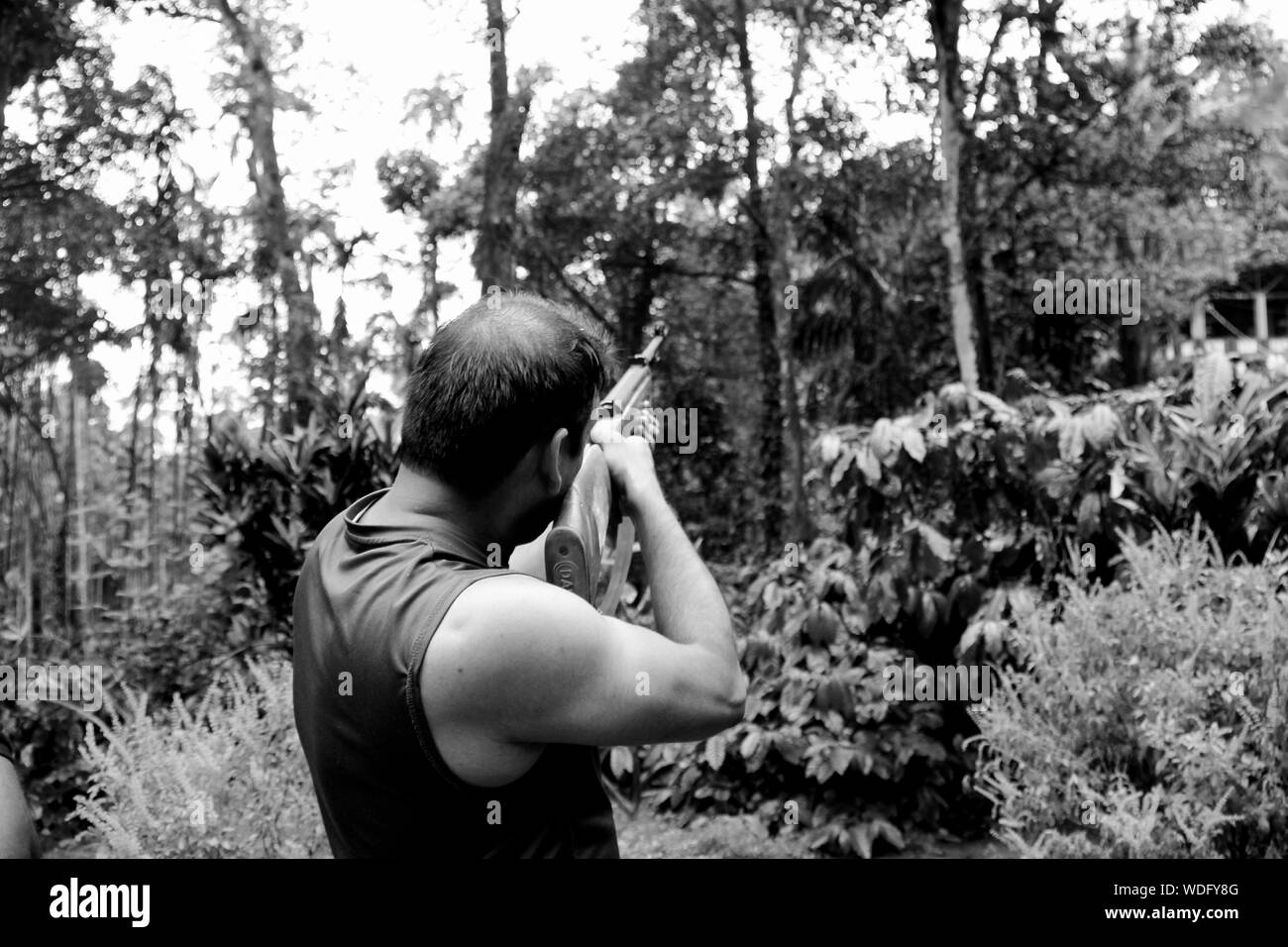 Man Aiming Rifle While Standing Against Trees Stock Photo - Alamy