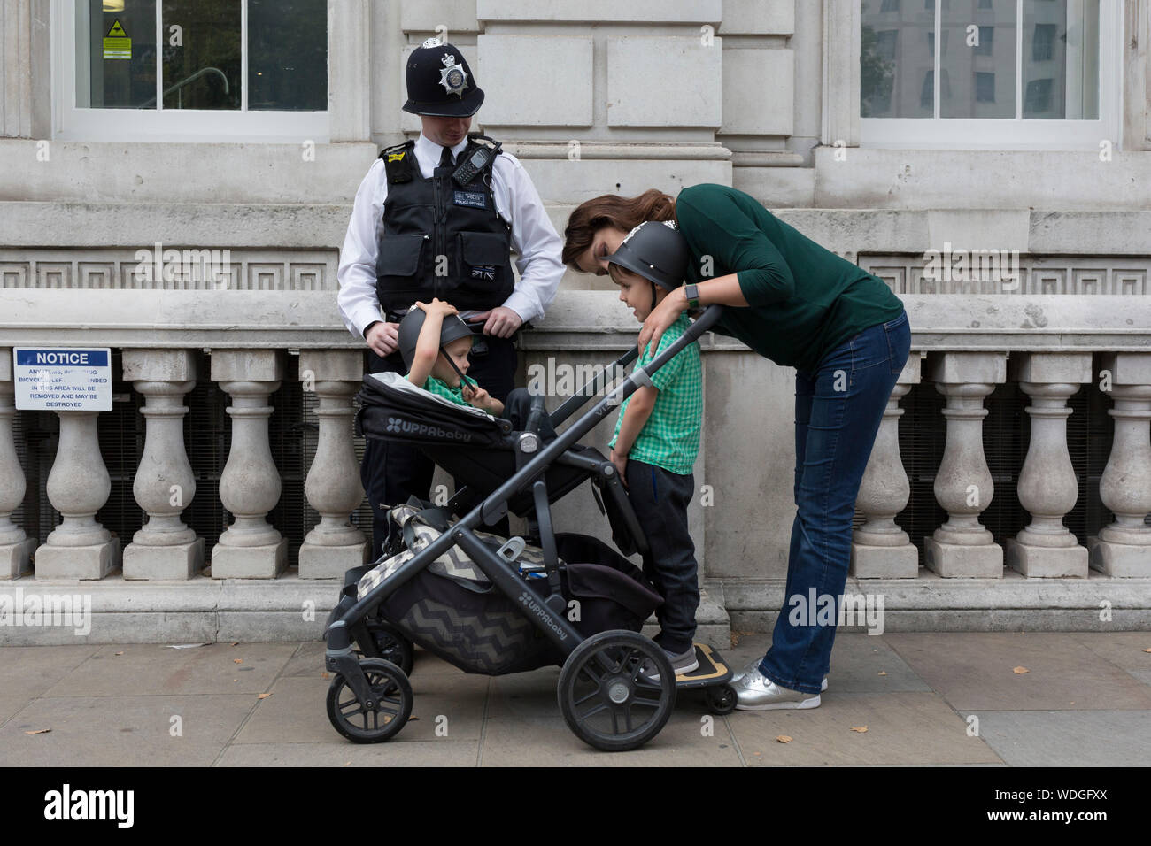 Two young boys wearing plastic police helmets are made happy by a real ...