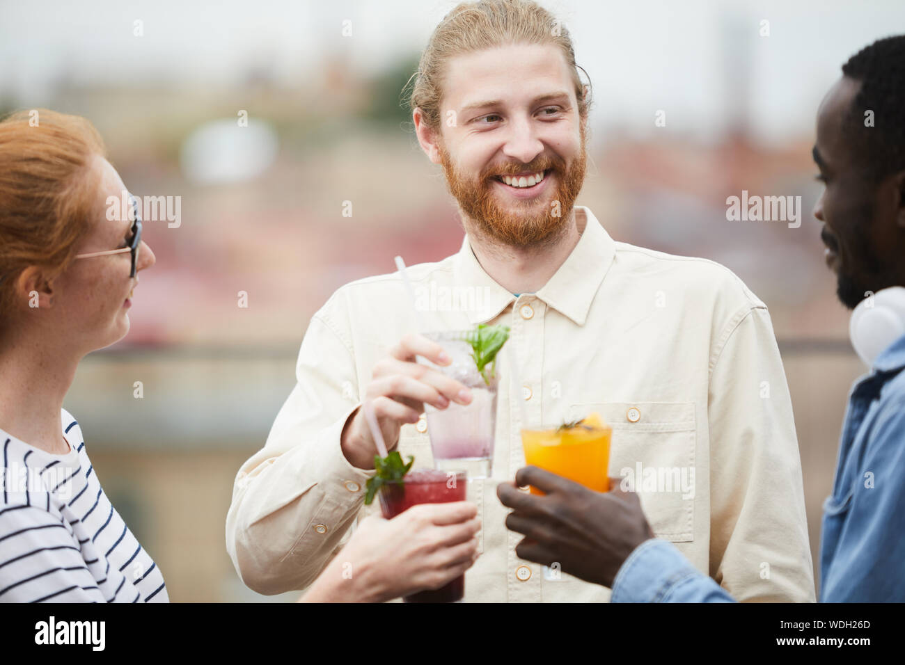 Young happy people standing and toasting with cocktails during party ...