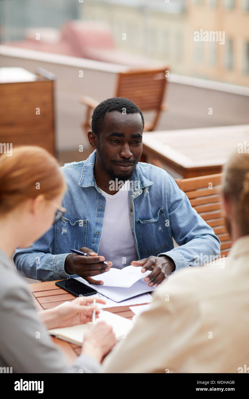 African young man in casual clothing making notes in his notepad while ...