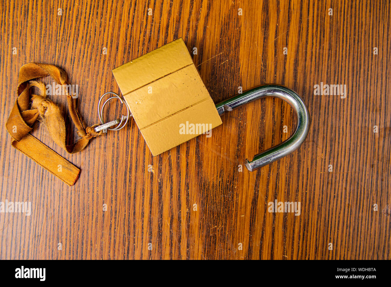 Padlock with key on the tape on a wooden background. Place for text ...
