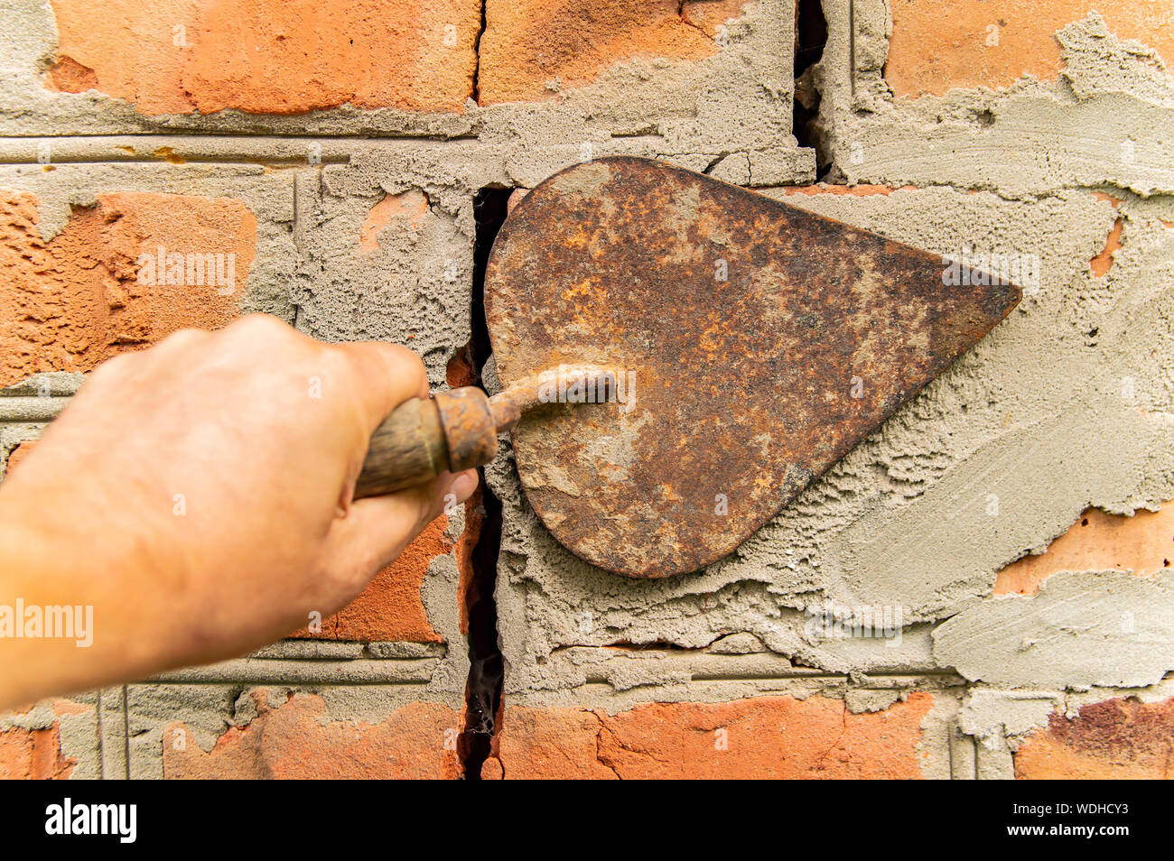 Spatula in the hand of the builder - repair of a brick wall. Place for ...