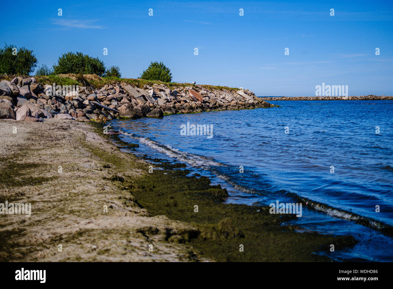 rocky seaside beach with blue water under summer sky and rocks on the ...