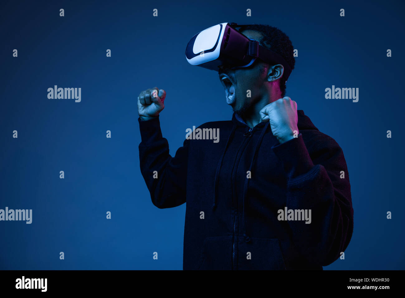 Young african-american man's screaming in VR-glasses in neon on ...
