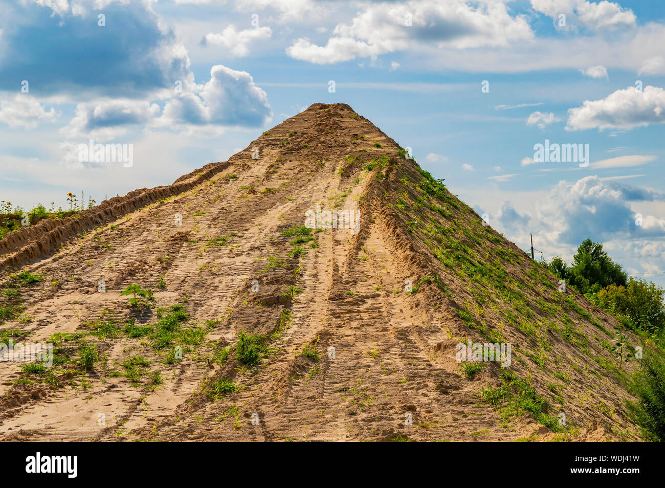 Sandy mountain against the blue sky with clouds. Background Stock Photo ...