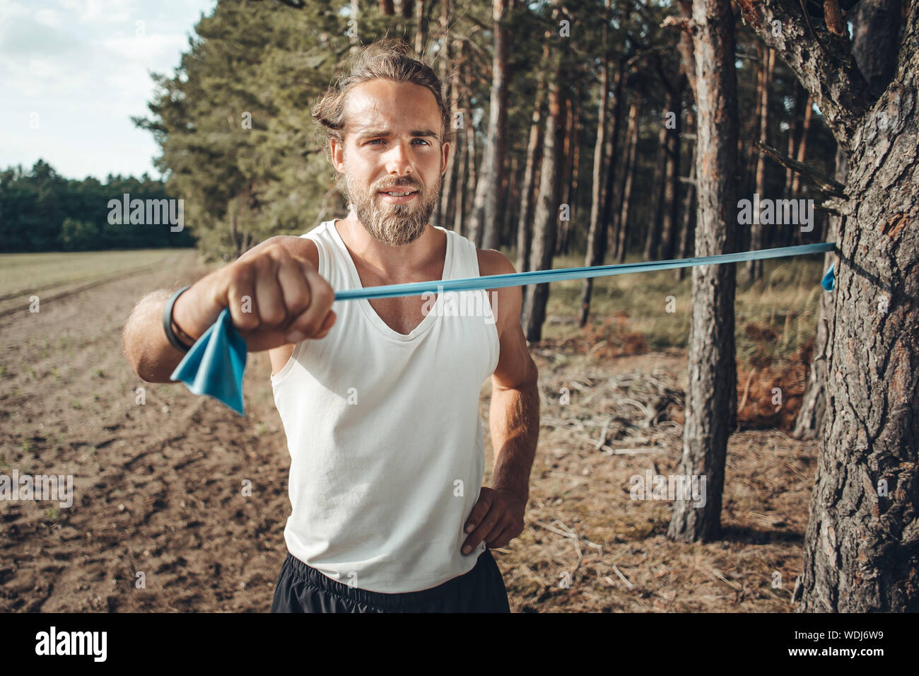 Young man using a resistance band to work out in nature Stock Photo - Alamy