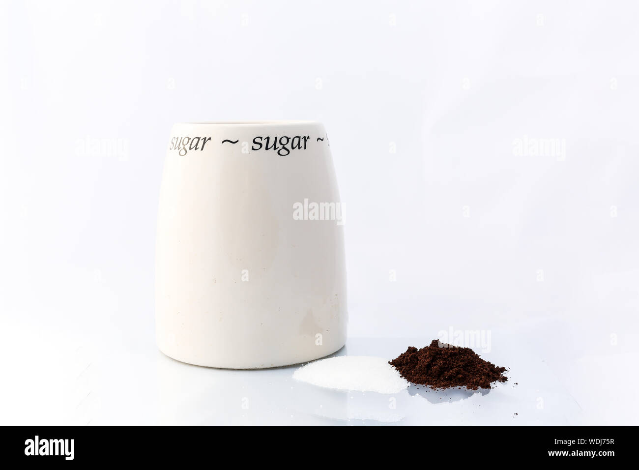 2 Piles of sugar next to an open sugar jar that is labelled. Shot ...