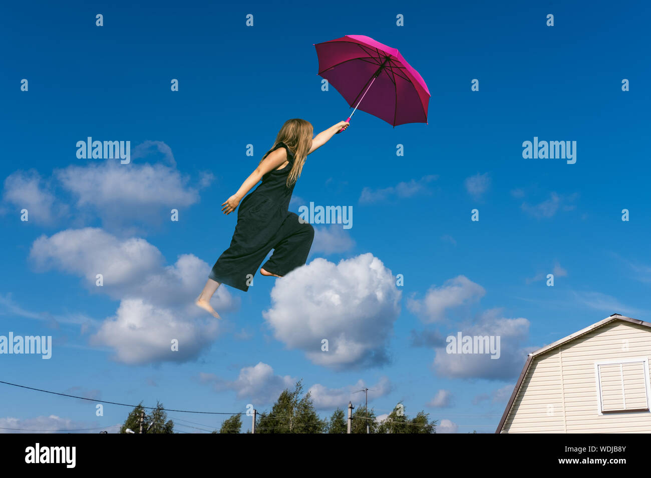 Cute girl jumping funny in clouds above earth. Small cheerful girl ...