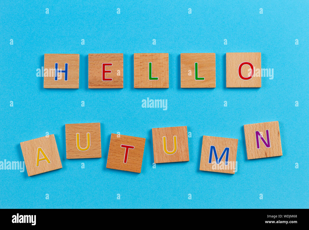 The words HELLO AUTUMN, spelt with wooden letter tiles over blue ...