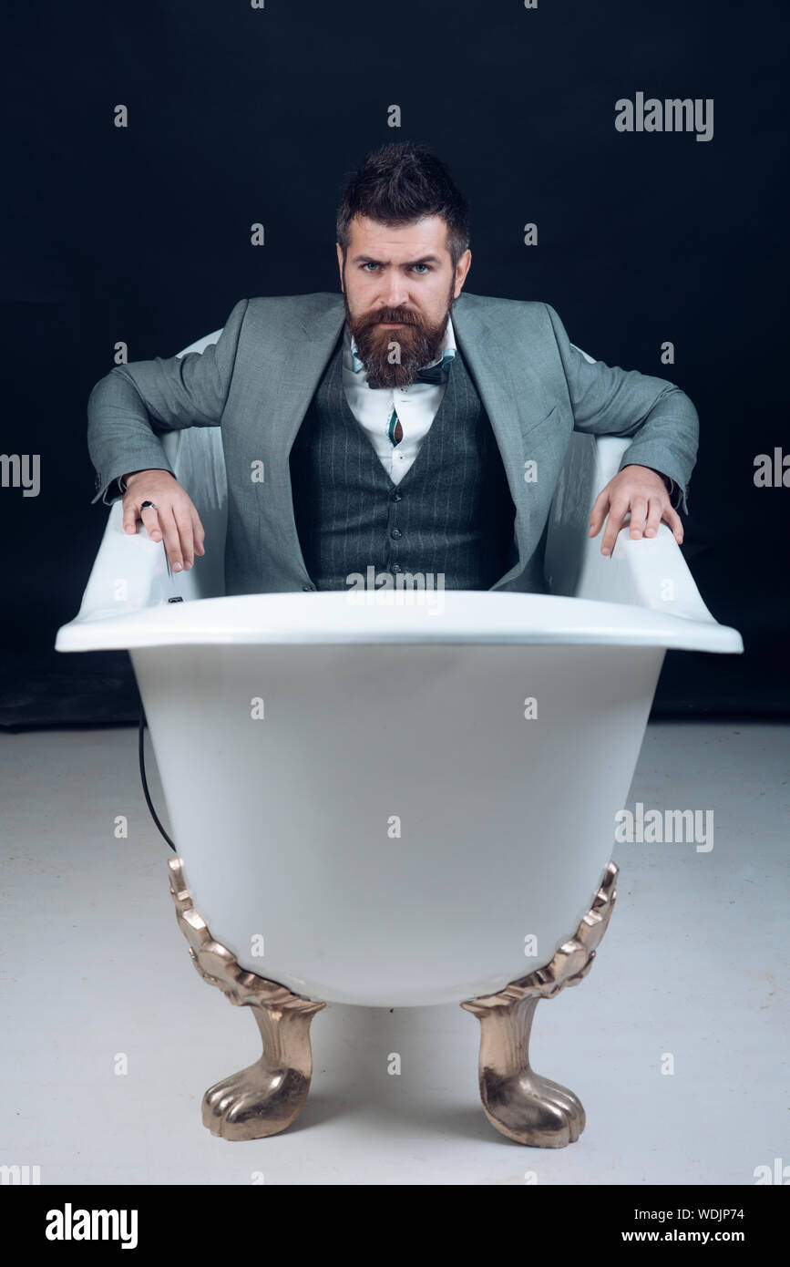 Hipster with stylish appearance in luxury old fashioned bathtub. Man or ...