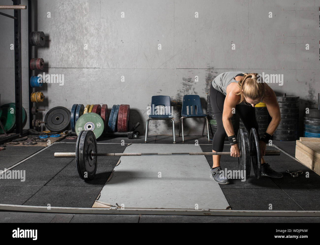 Young female power lifter loading weights onto barbell Stock Photo - Alamy
