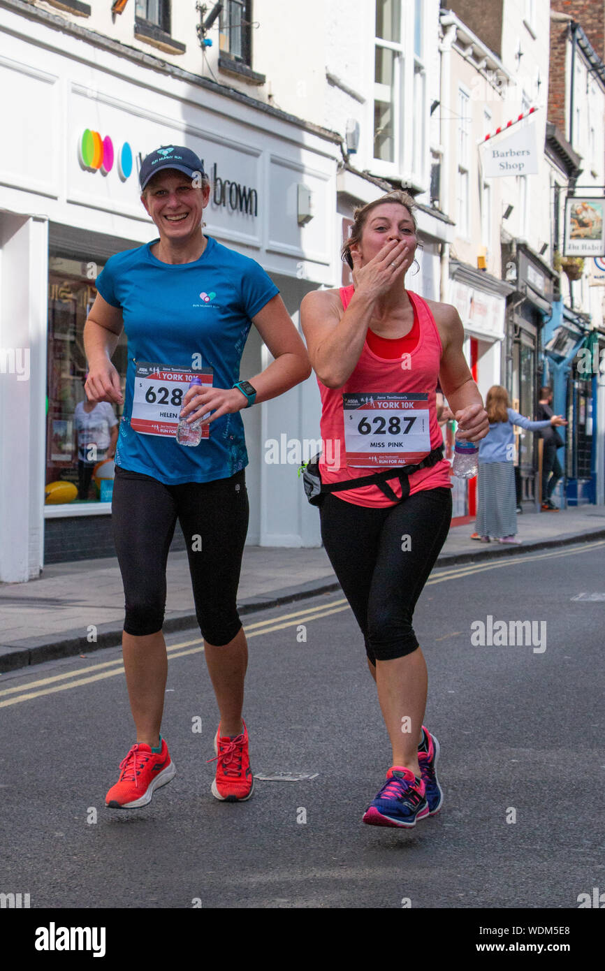 Two women jog down the streets during the York 10k in August 2019 Stock ...
