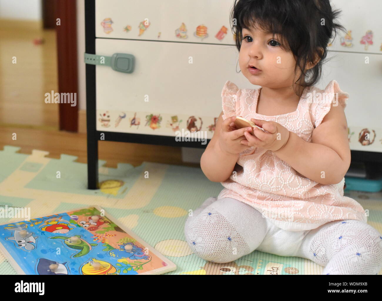 Cute baby girl plays with puzzle pieces in nursery Stock Photo - Alamy