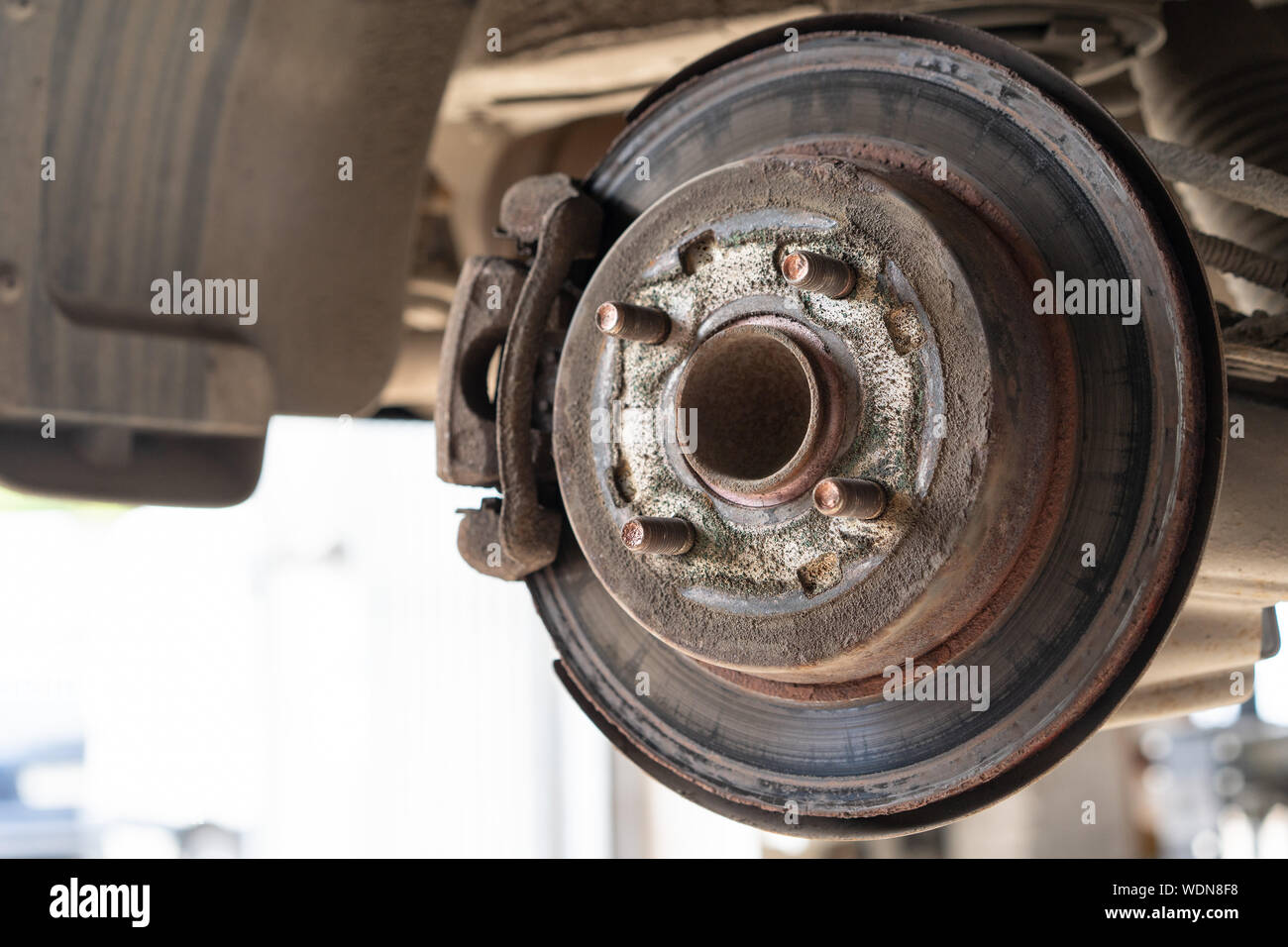 Old worn brake discs on a passenger car. Car on a lift in a car service ...