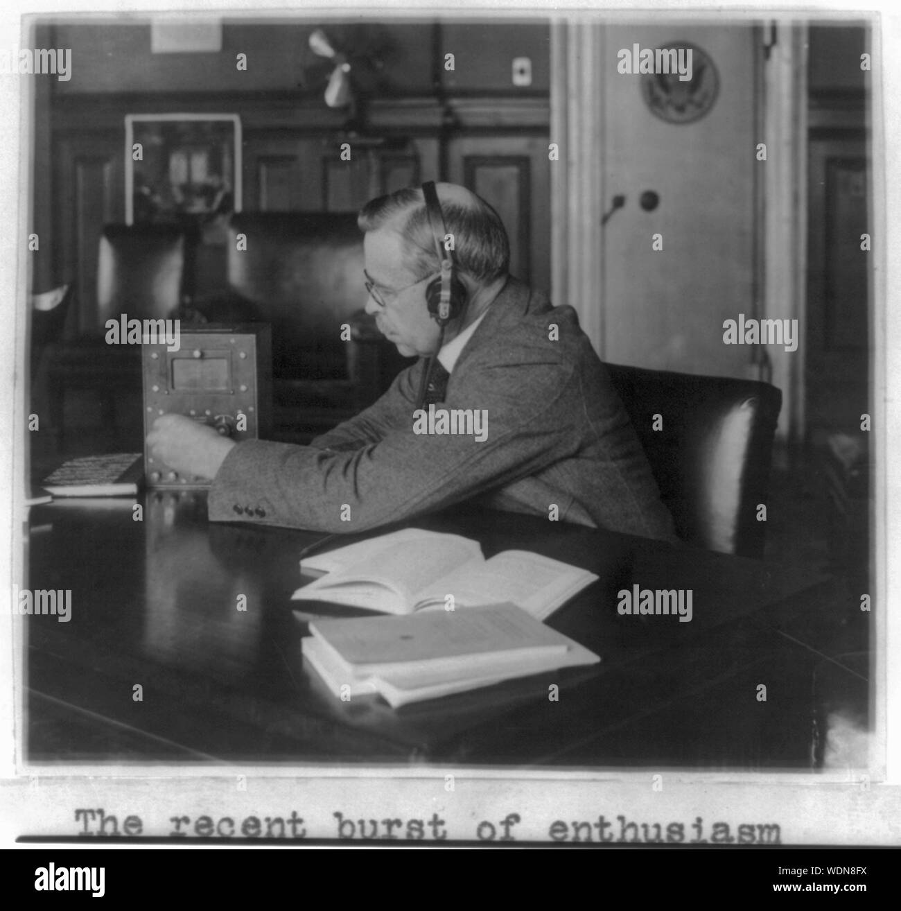 Government official seated at his desk wearing head phones and tuning ...