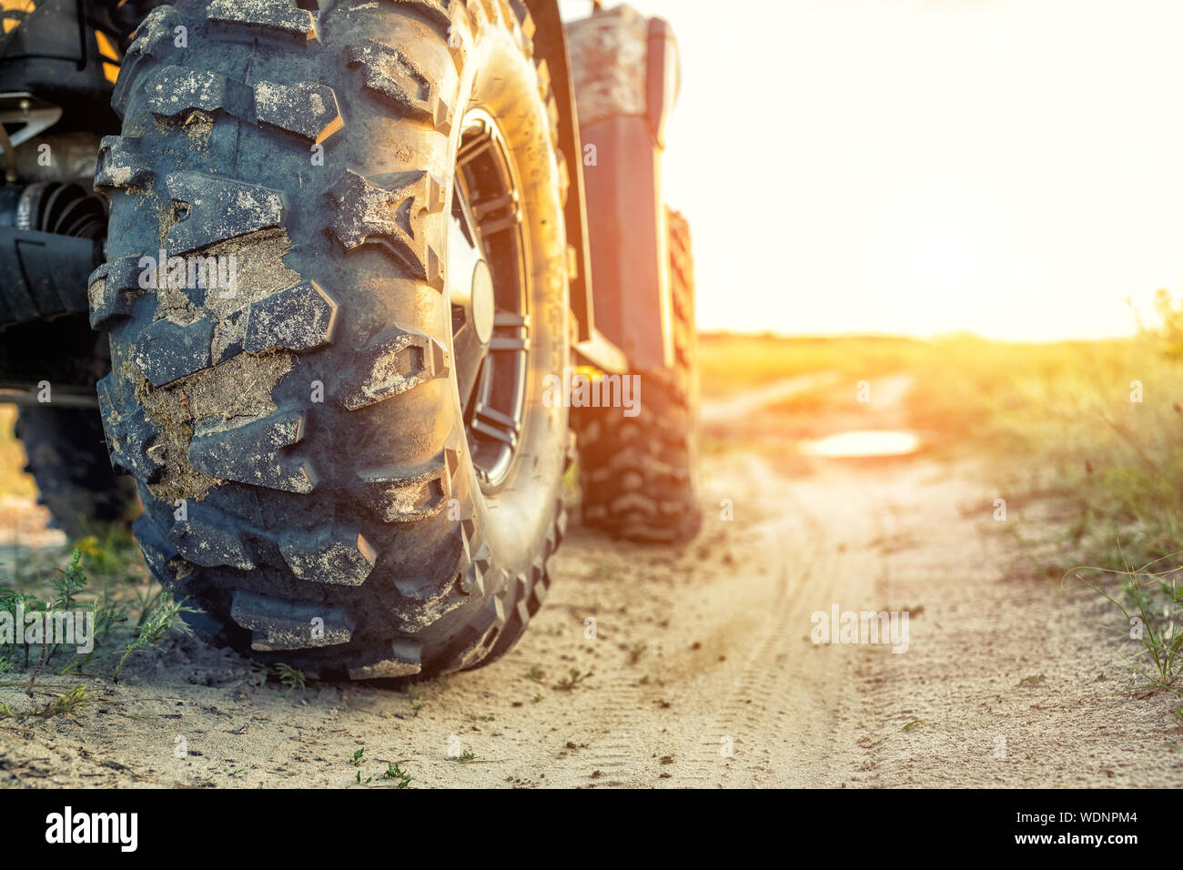 Close-up tail view of ATV quad bike on dirt country road at evening ...