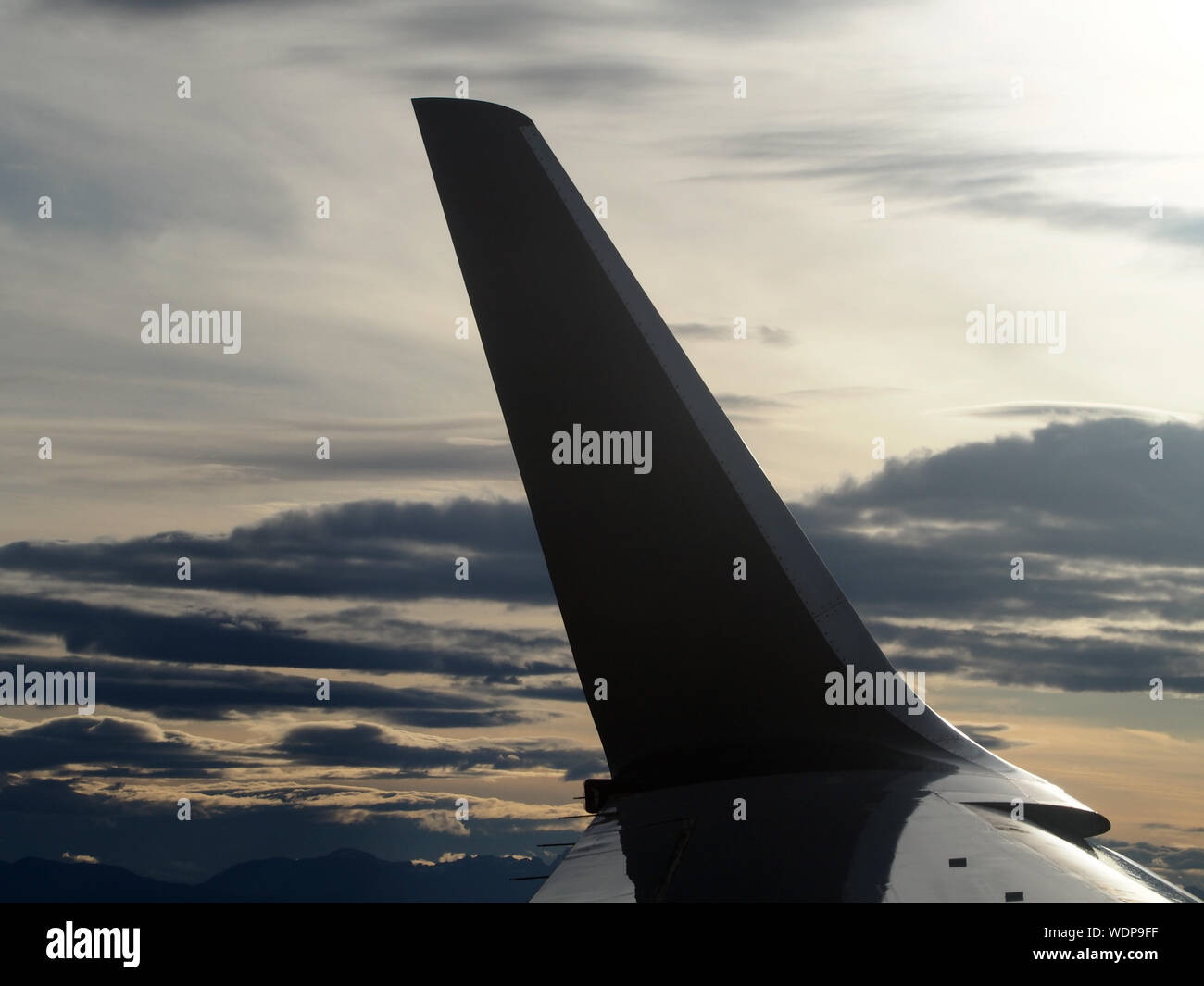 Aerial high in the sky, shot from clouds level, with the wing of a ...