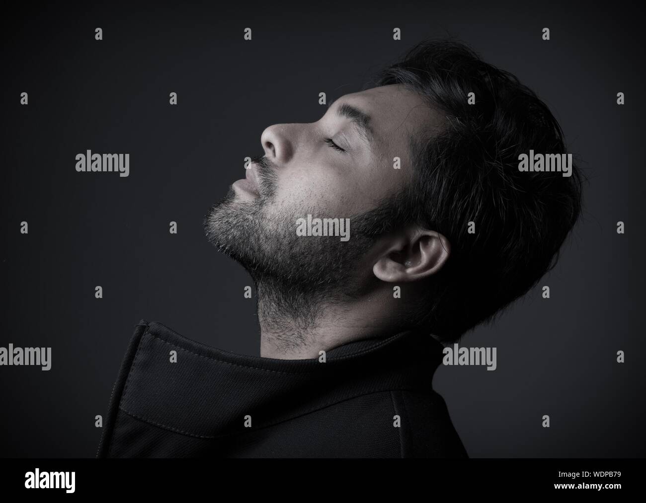 Side View Of Handsome Young Man With Eyes Closed Against Black ...