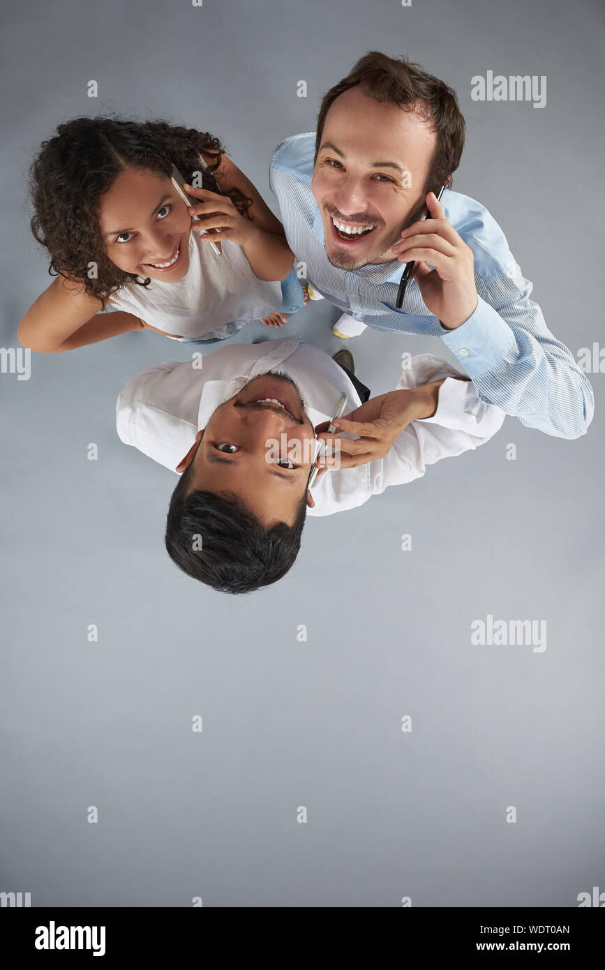 Smiling people with smartphones above top view in gray studio ...