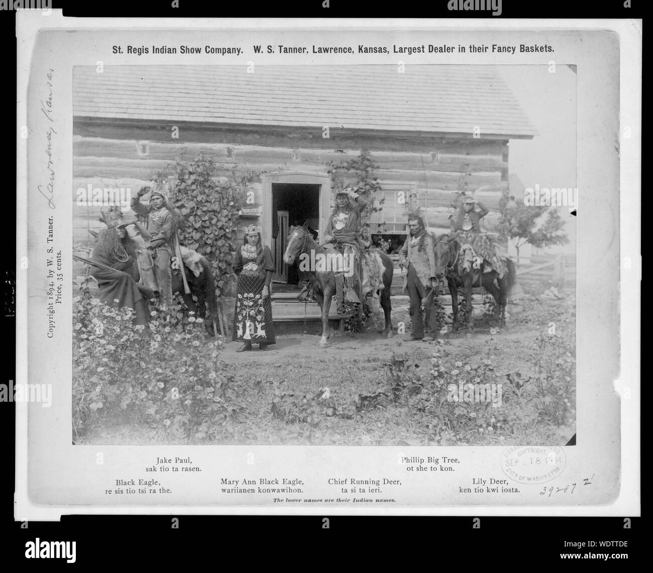 Group portrait of St. Regis Mohawk men and women in costume outside log ...
